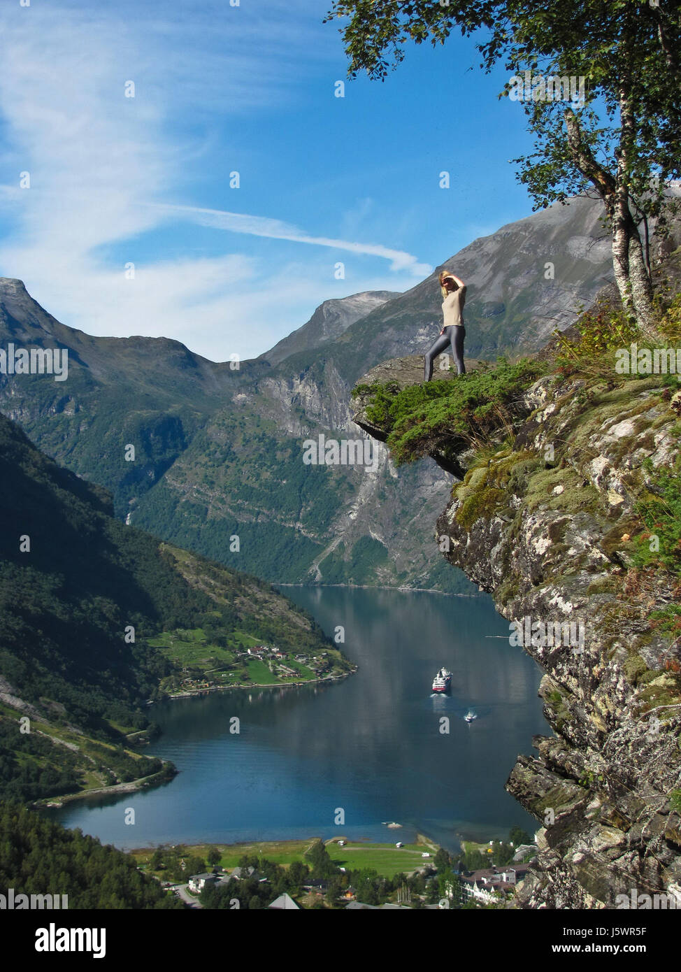 The girl is standing on the edge of the cliff, the Geiranger fjord ...