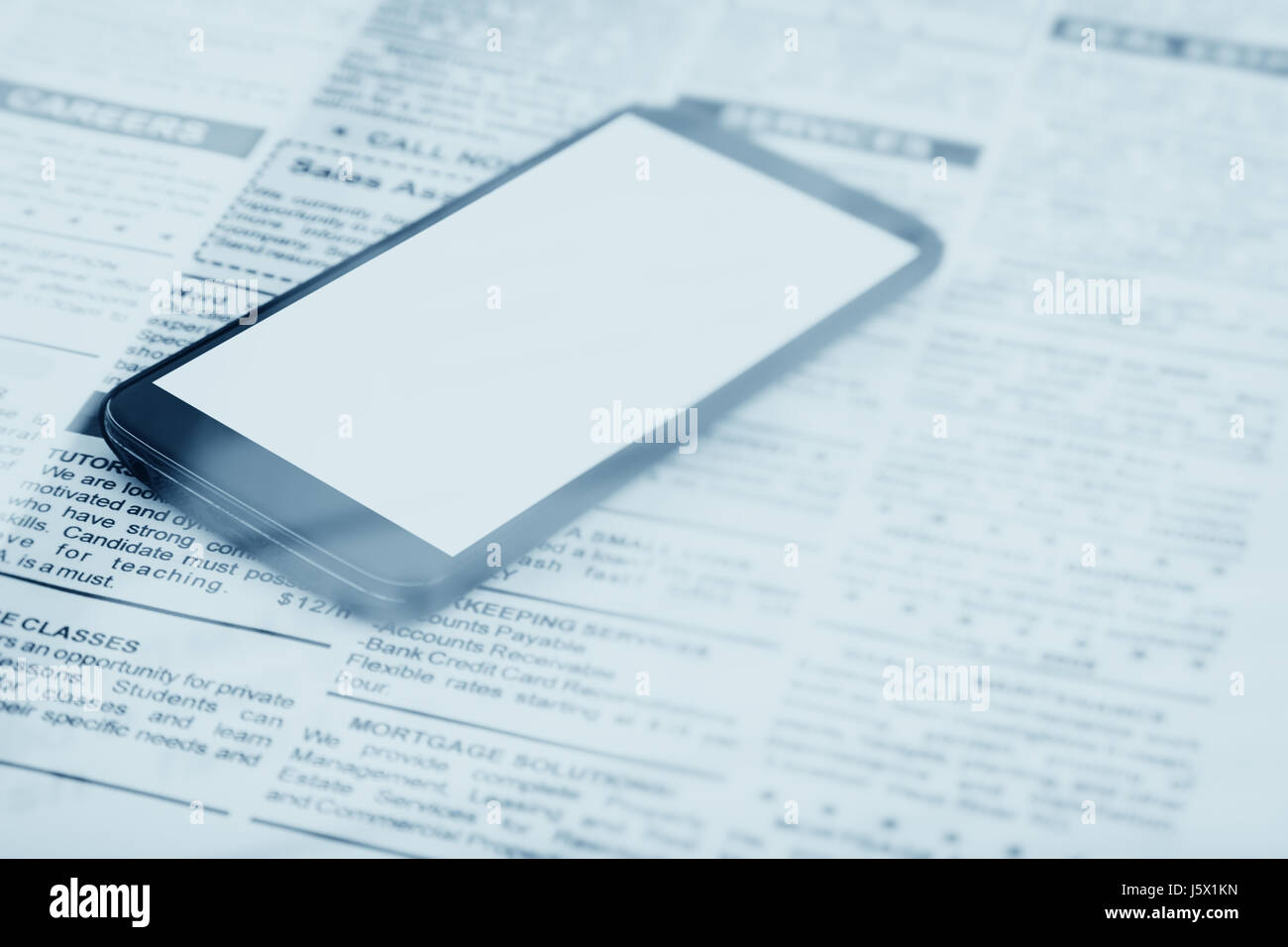 Fake newspaper and smartphone with blank screen. business communication ...