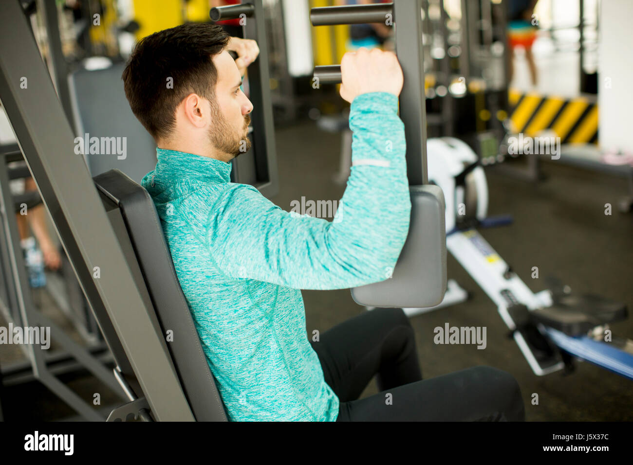 Young man exercise on an exercise machine at the gym Stock Photo - Alamy