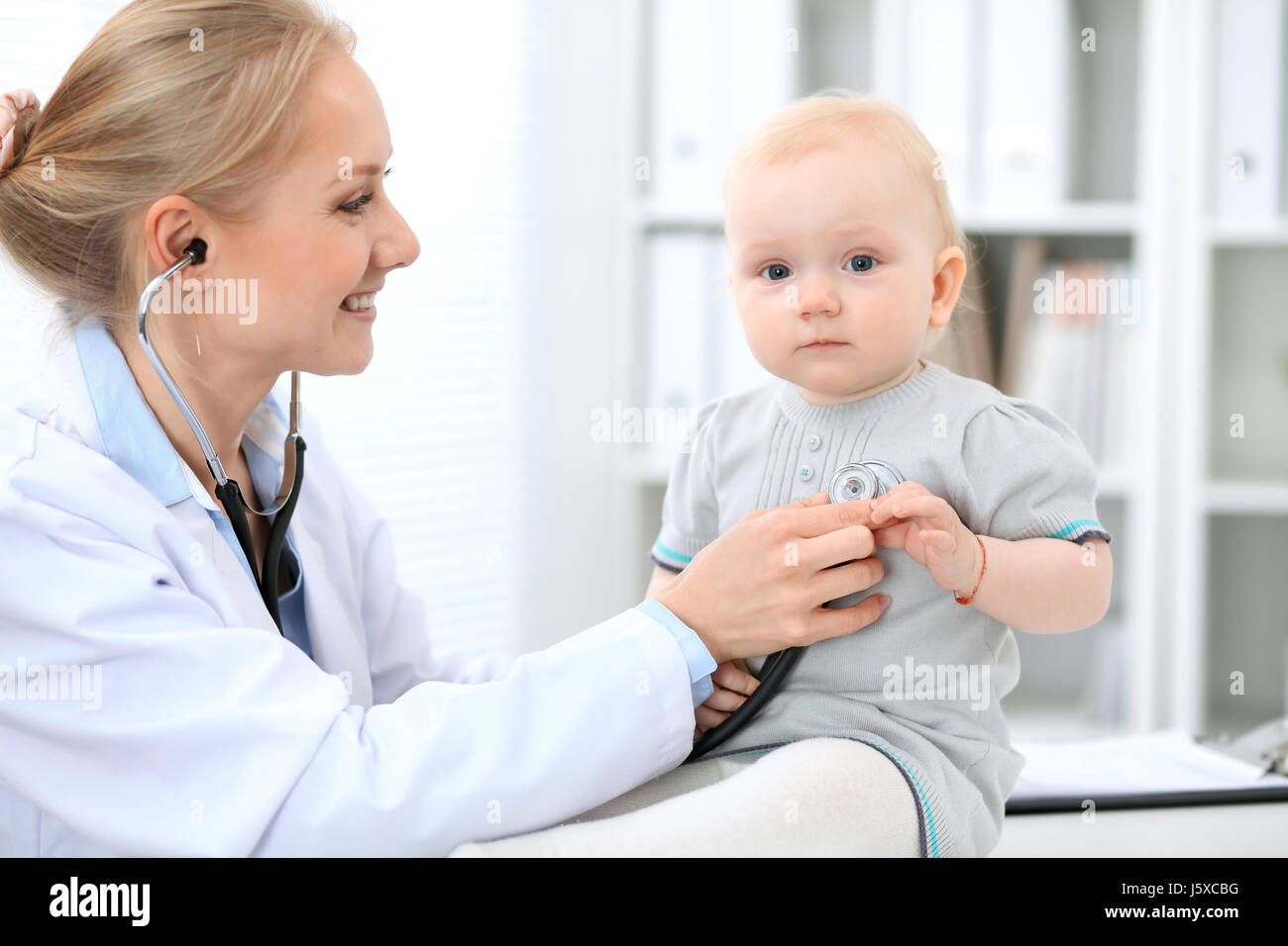Pediatrician is taking care of baby in hospital. Little girl is being ...