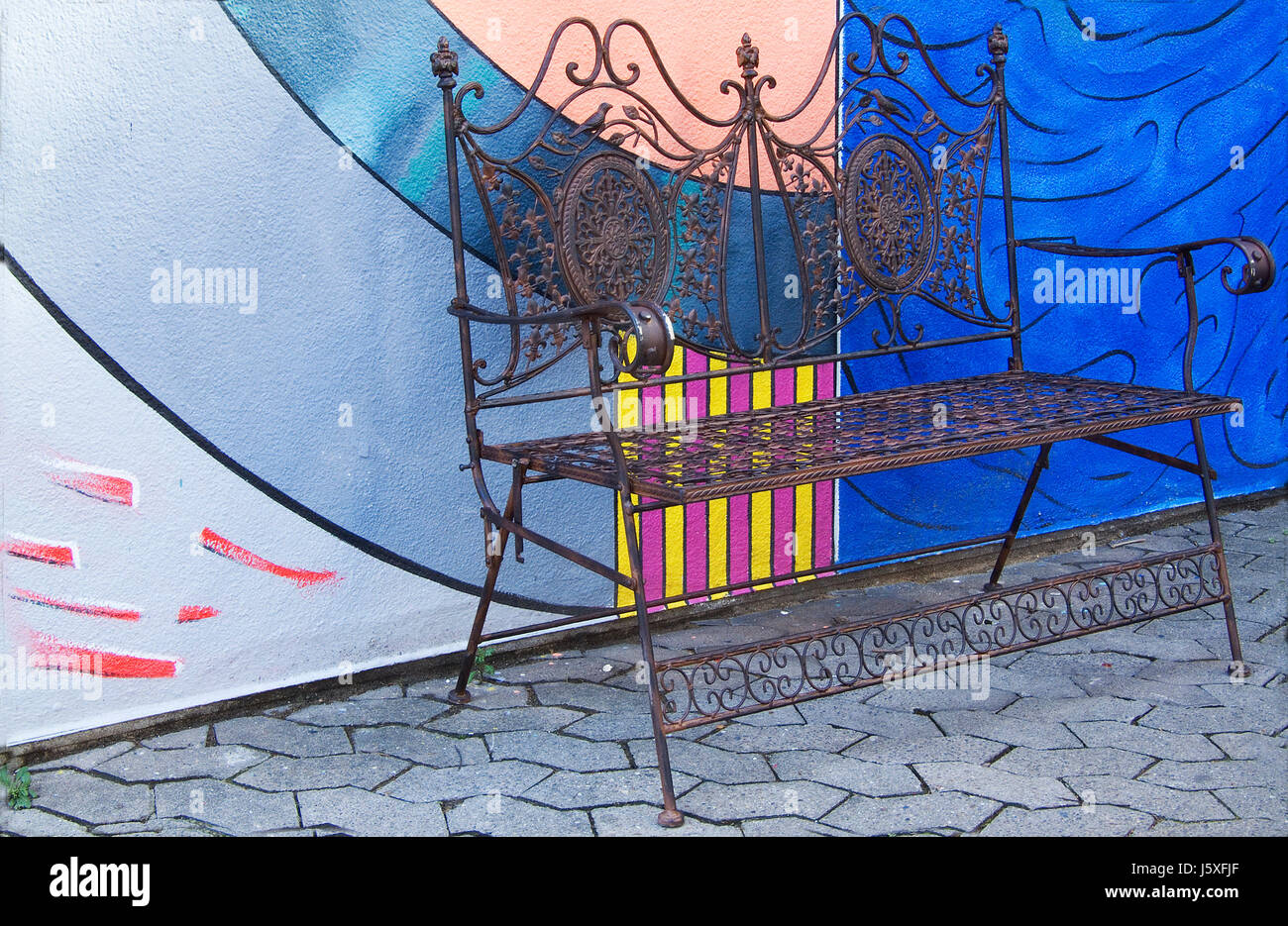 wrought iron bench in front of mural Stock Photo - Alamy