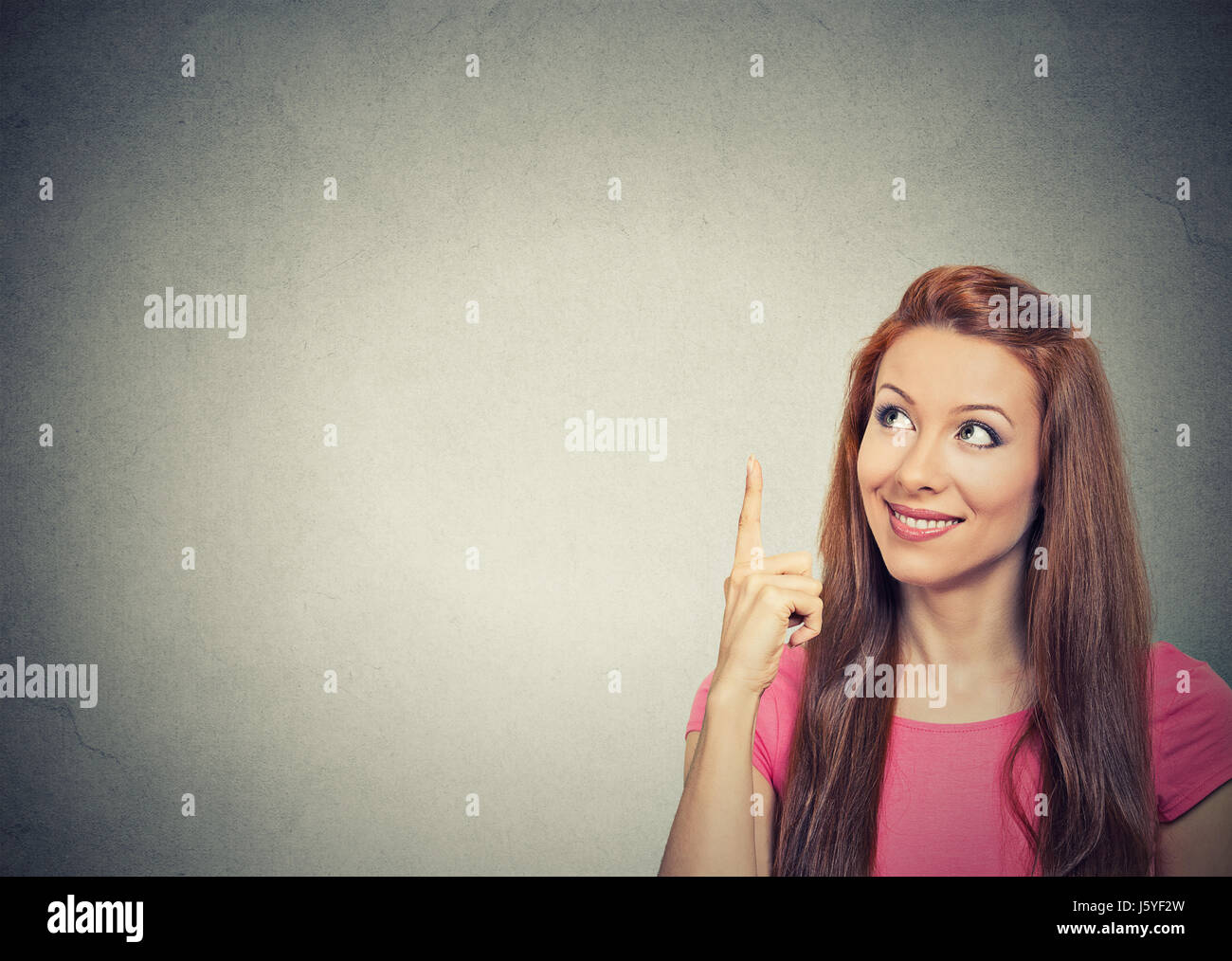 Portrait happy beautiful woman thinking looking up pointing with finger ...
