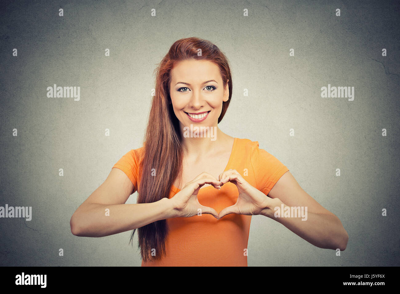 Closeup portrait smiling cheerful happy young woman making heart sign ...