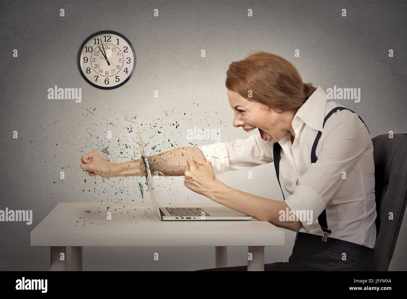 Angry, furious businesswoman throws a punch into computer, screaming ...