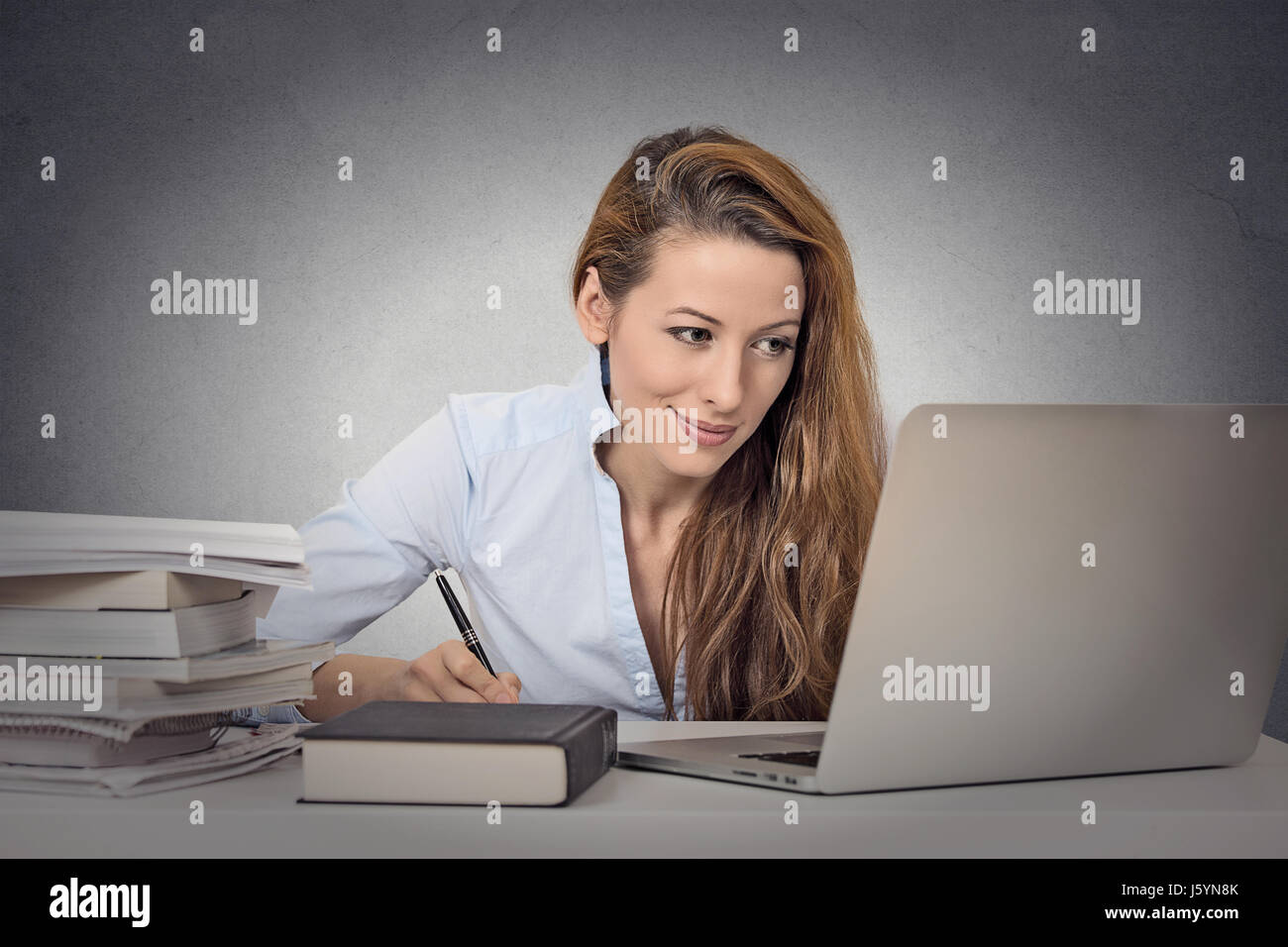 Portrait young student studying hard working on computer taking notes ...