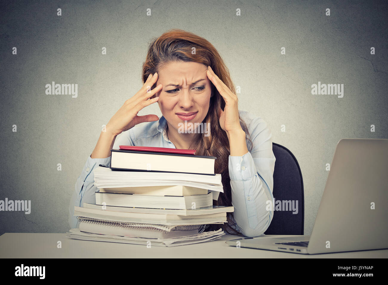 Too much work tired stressed young woman sitting at her desk with books ...