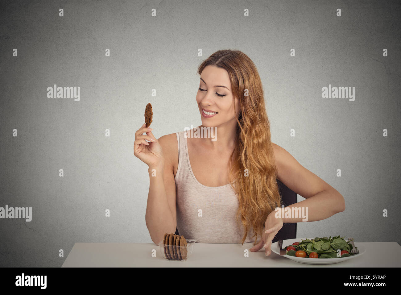 Happy young woman decided to eat sweet cookie not healthy food green ...