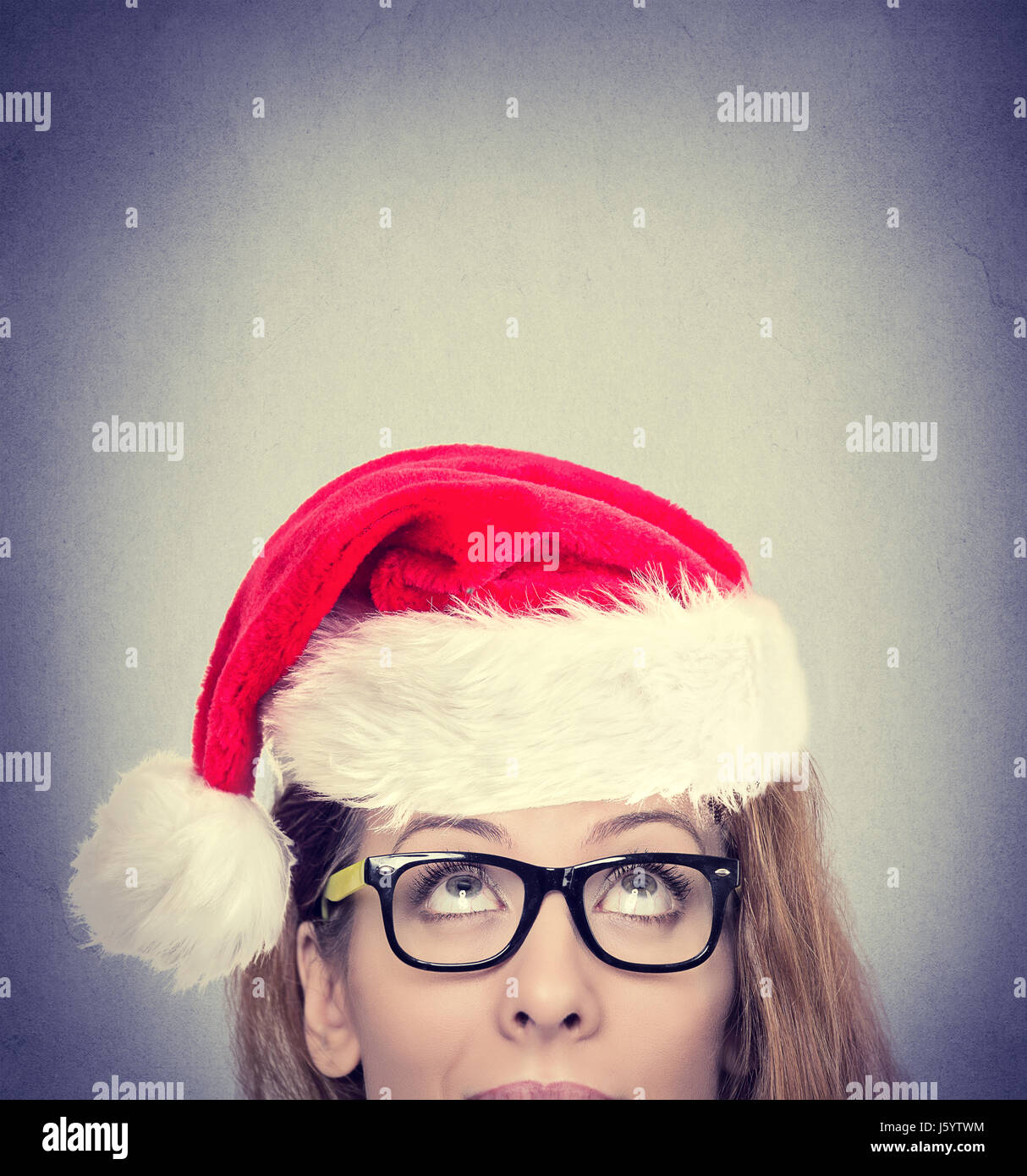 closeup headshot woman with red Santa Claus hat looking up at copy ...