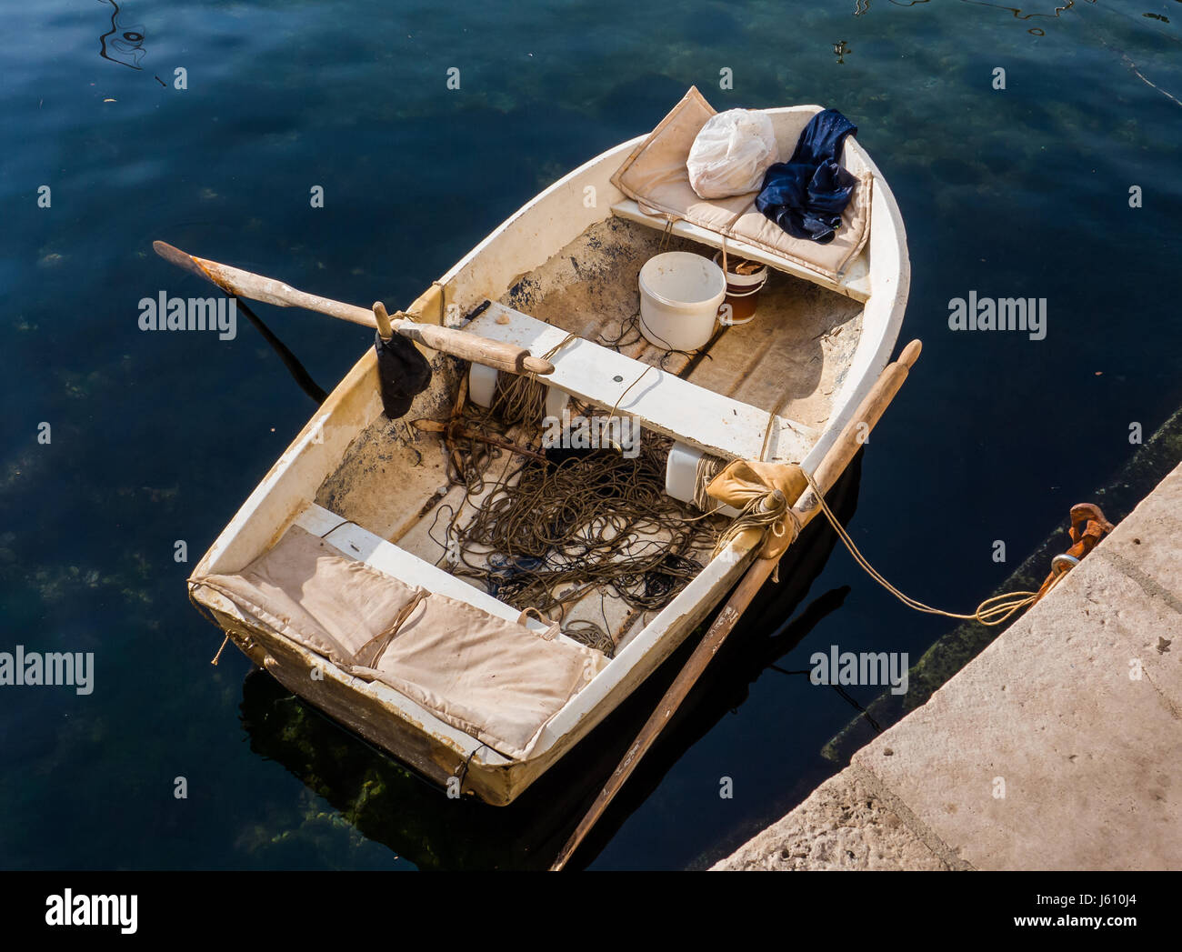 Small wooden row boat in the sea tied to the dock Stock Photo - Alamy