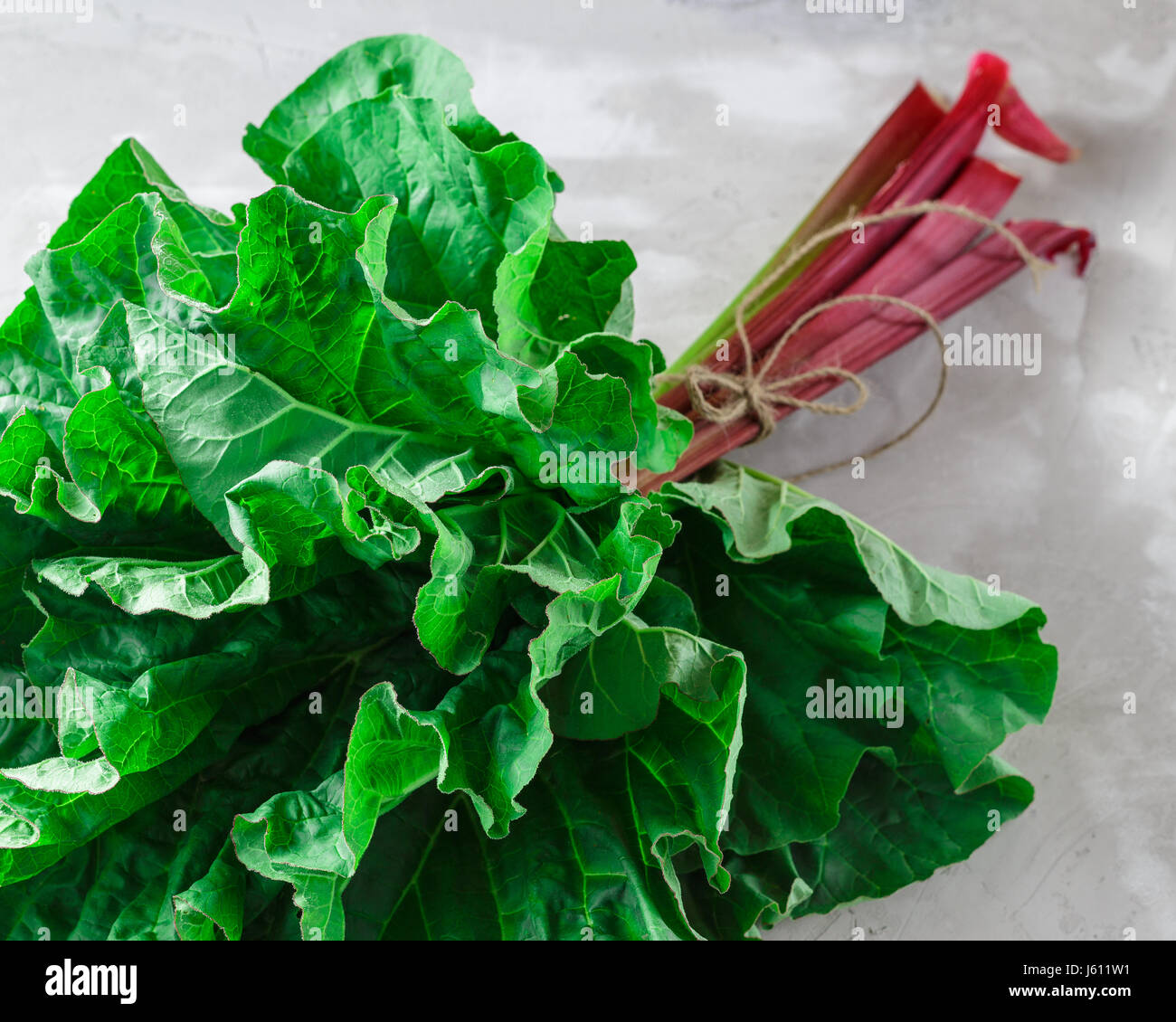 Fresh organic rhubarb stems with leaves on grey concrete stone ...