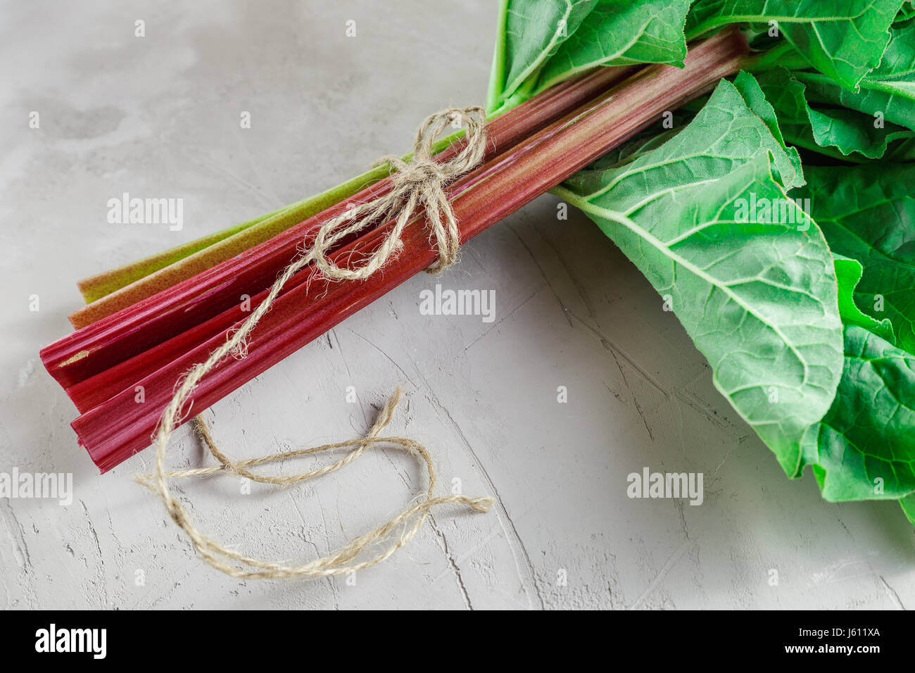 Fresh organic rhubarb stems with leaves on grey concrete stone ...