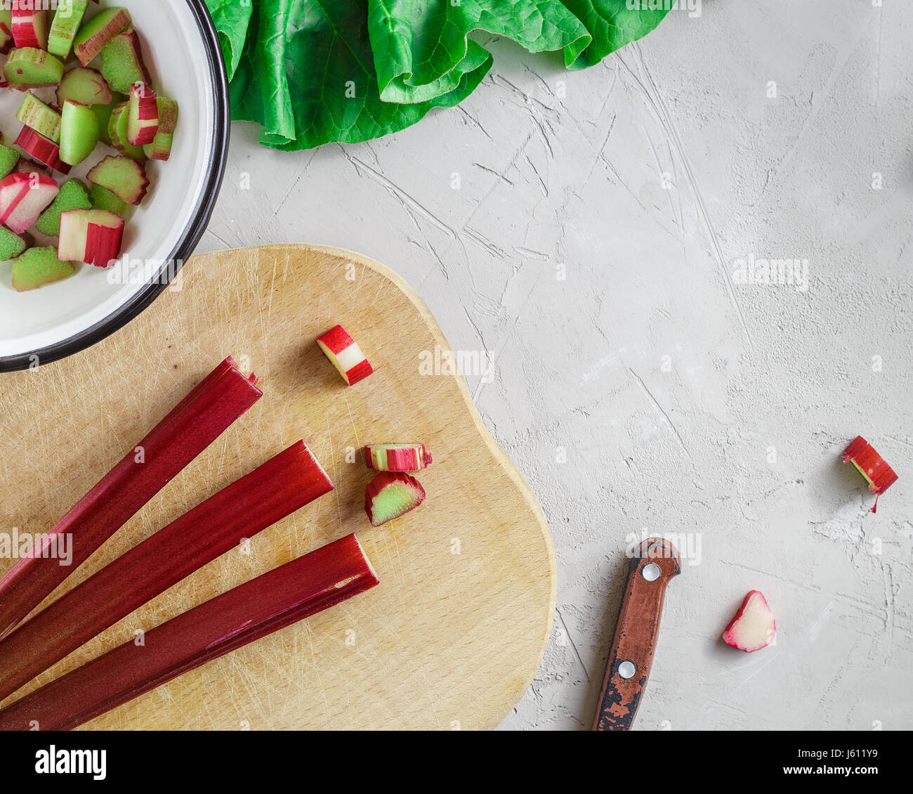 Fresh organic rhubarb stems on wooden cutting board over grey concrete ...