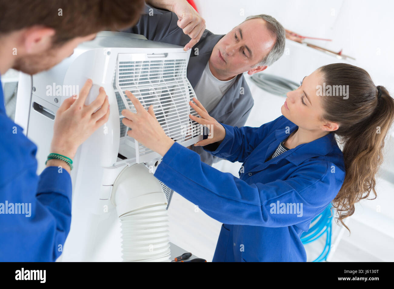 Trainees working on an air conditioning unit Stock Photo - Alamy