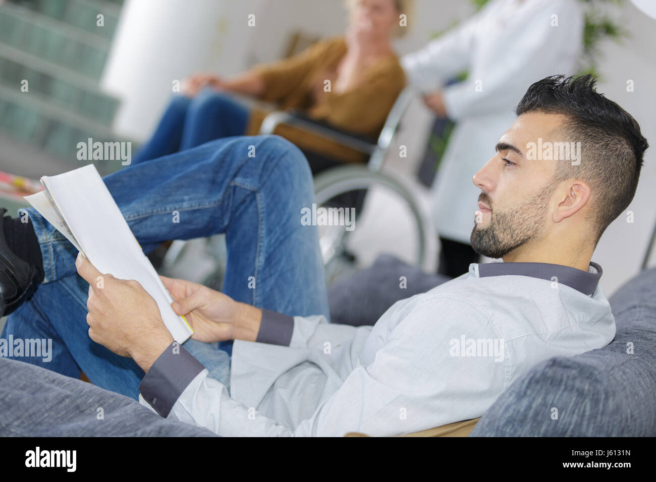 Man reading paperwork in hospital waiting room Stock Photo - Alamy