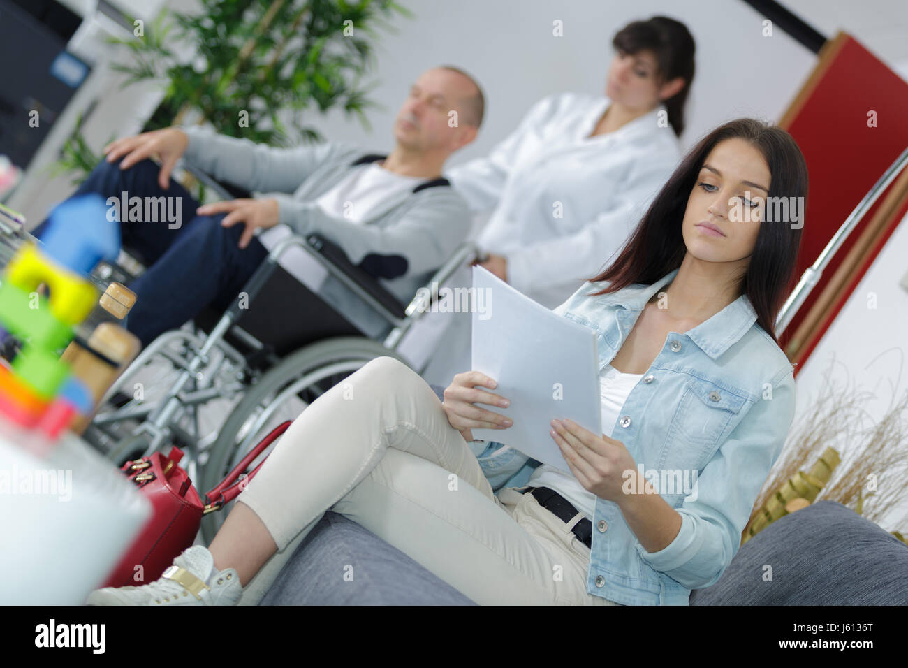 Lady reading paperwork in medical waiting room Stock Photo - Alamy