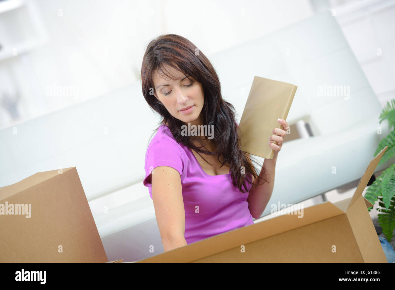 Woman unpacking items from cardboard box Stock Photo - Alamy