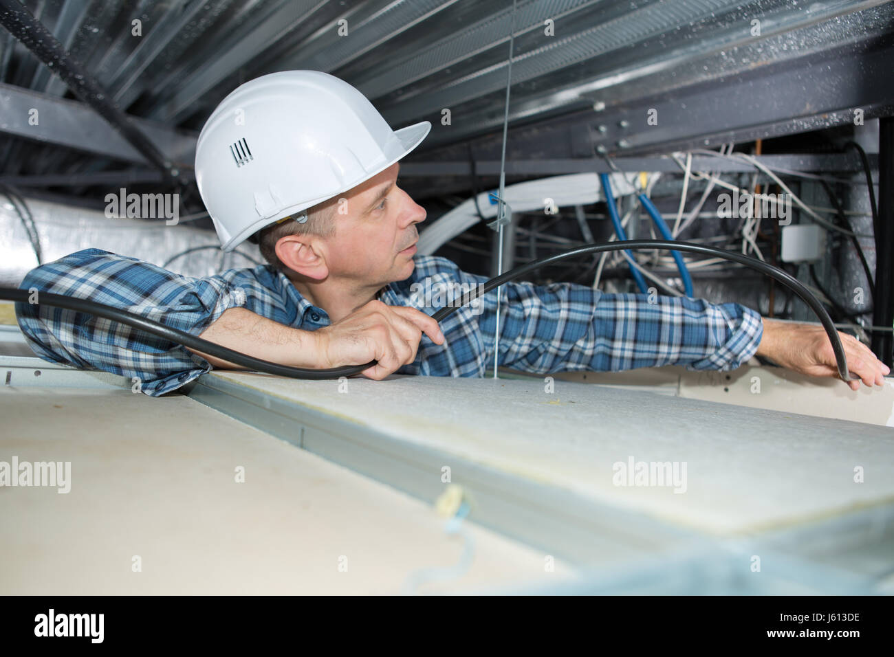 Electrician installing cables into confined space Stock Photo - Alamy