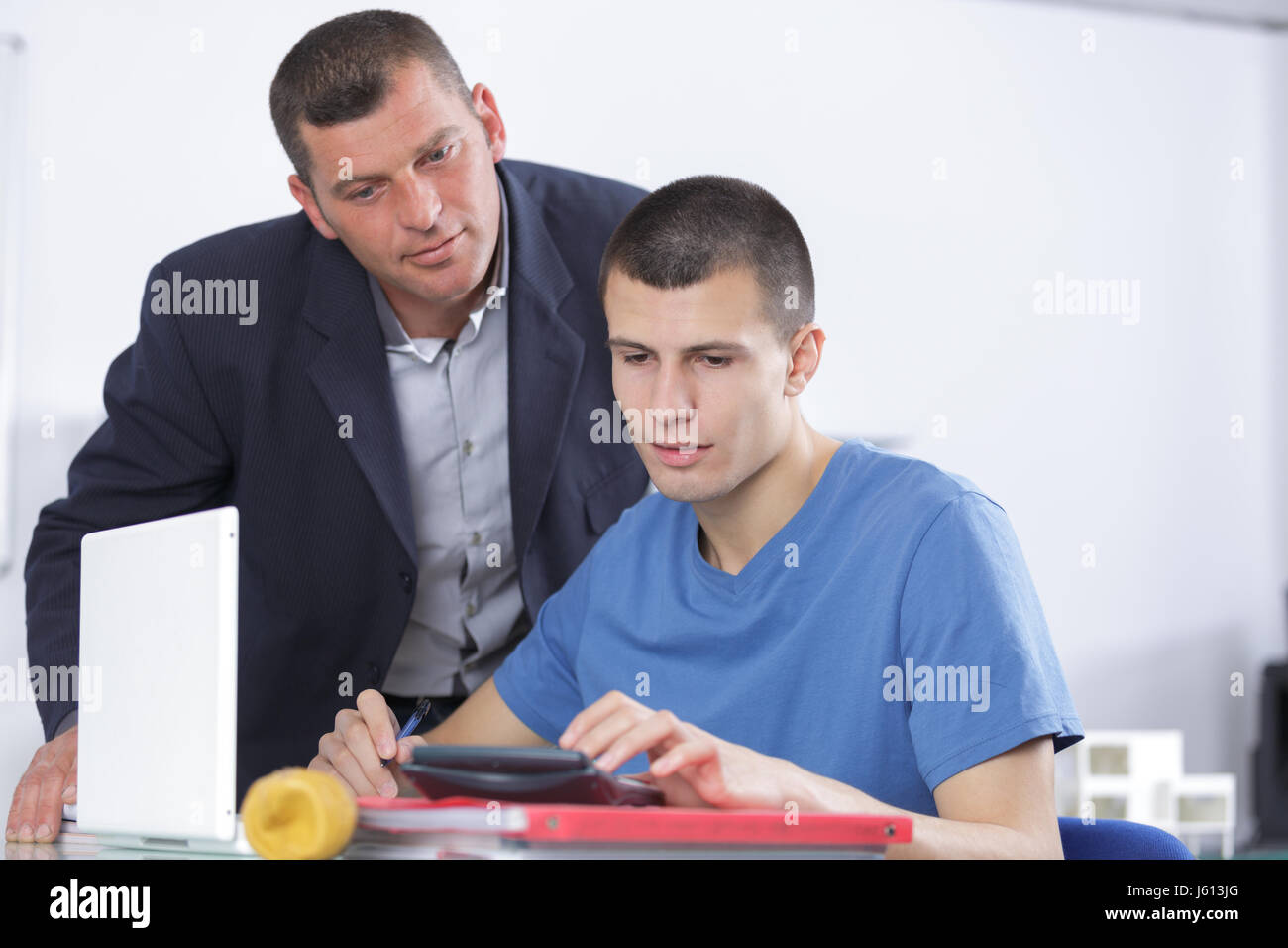 Older man helping younger man on computer Stock Photo - Alamy