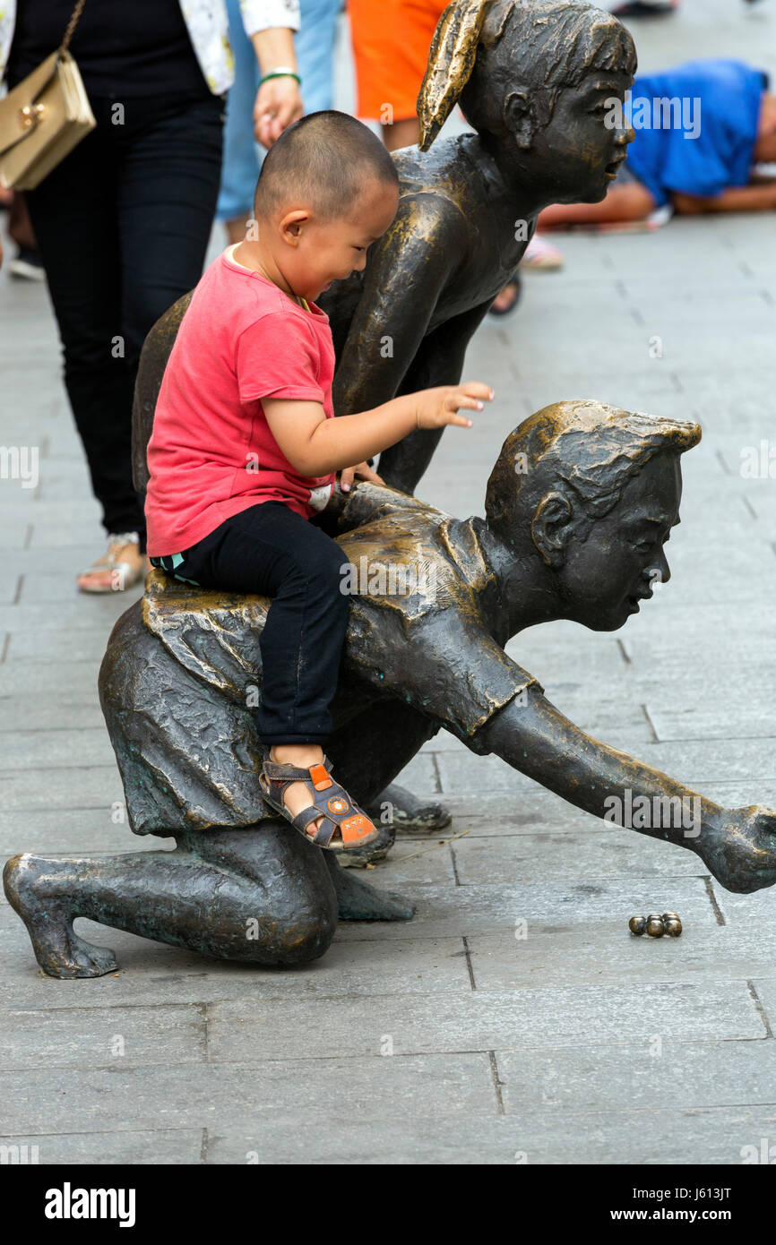 Chinese boy playing with statue, Yinchuan, Ningxia, China Stock Photo ...