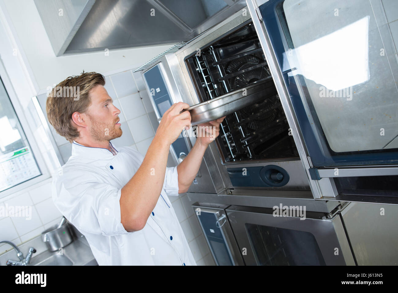 Chef taking tray from oven Stock Photo - Alamy