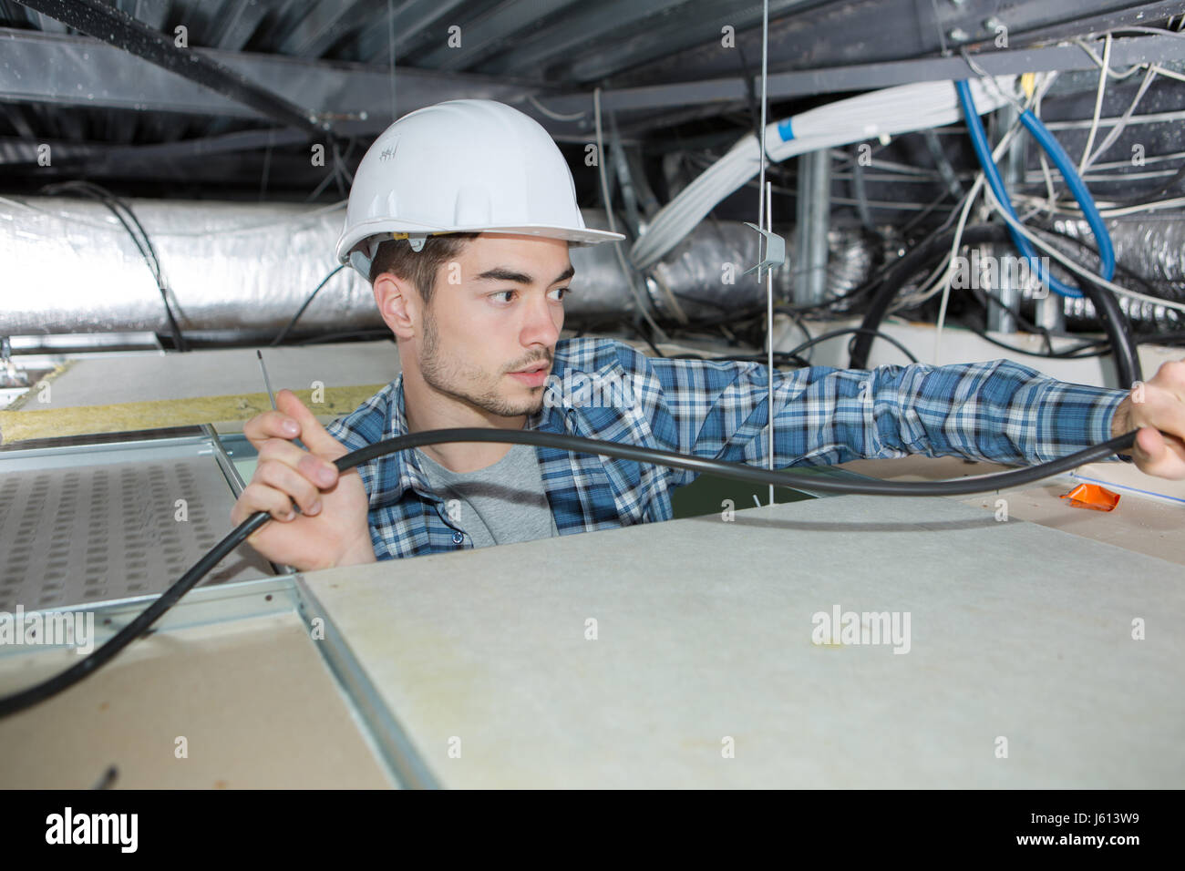 Electrician working in roof space Stock Photo - Alamy