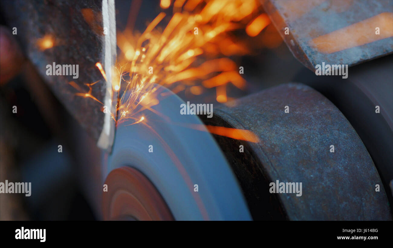 Close up on the hands of a blacksmith sharpening an axe on an ...