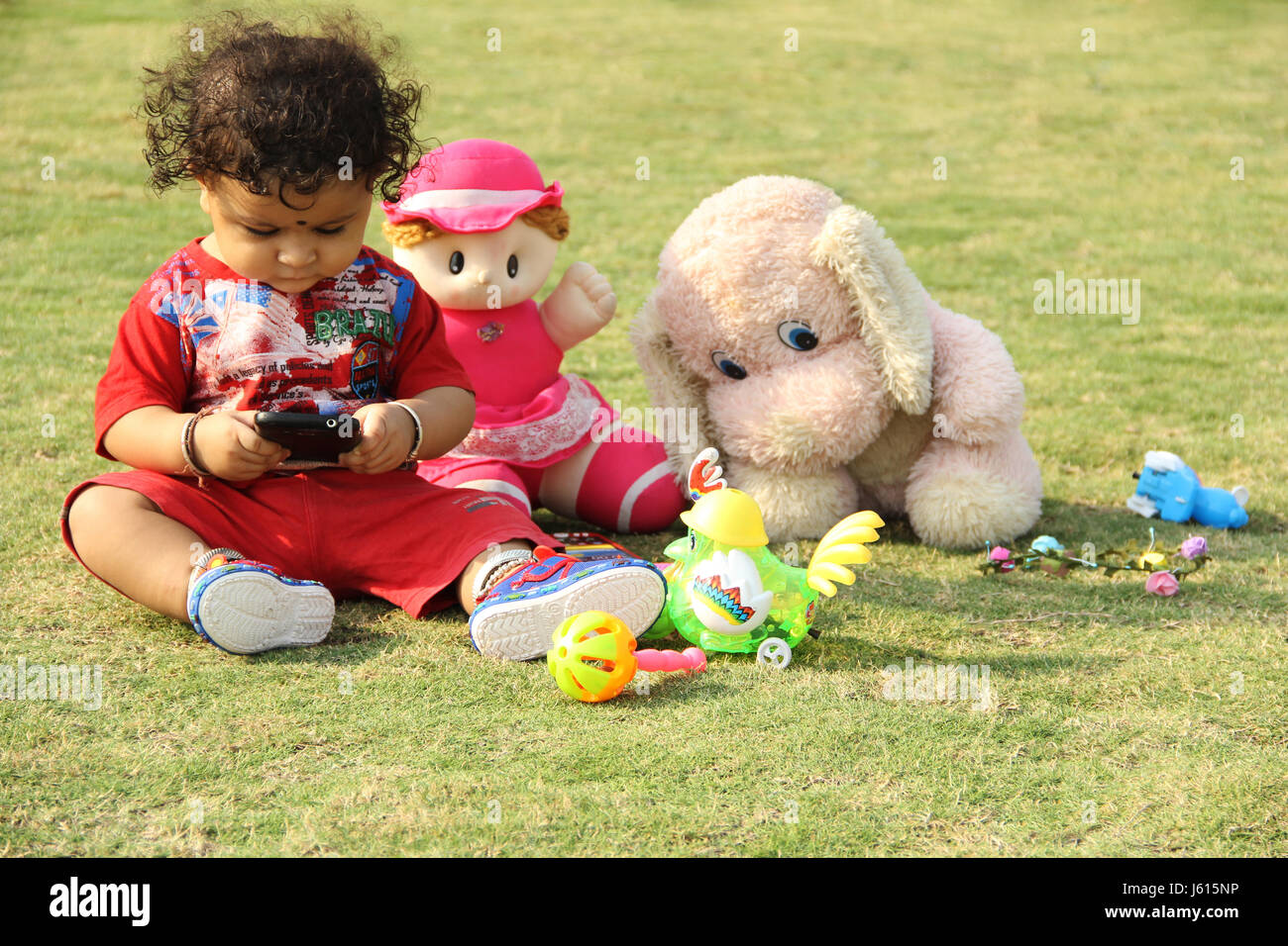 Little child looking at mobile ignoring his toys in garden Stock Photo ...