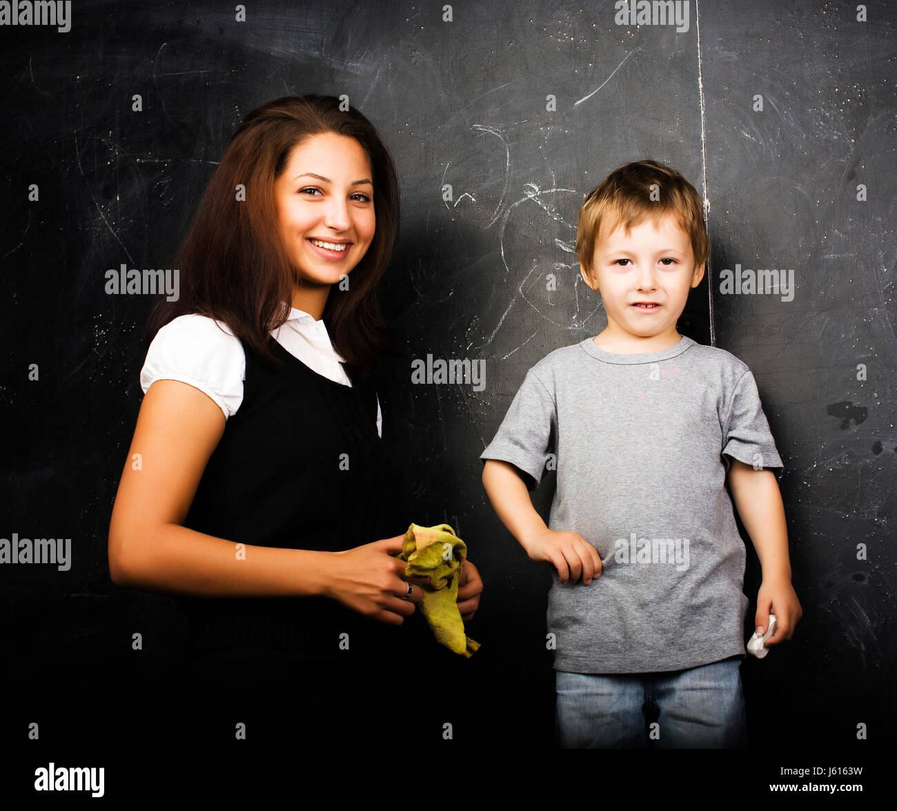 little cute boy with young teacher in classroom studying at blac Stock ...