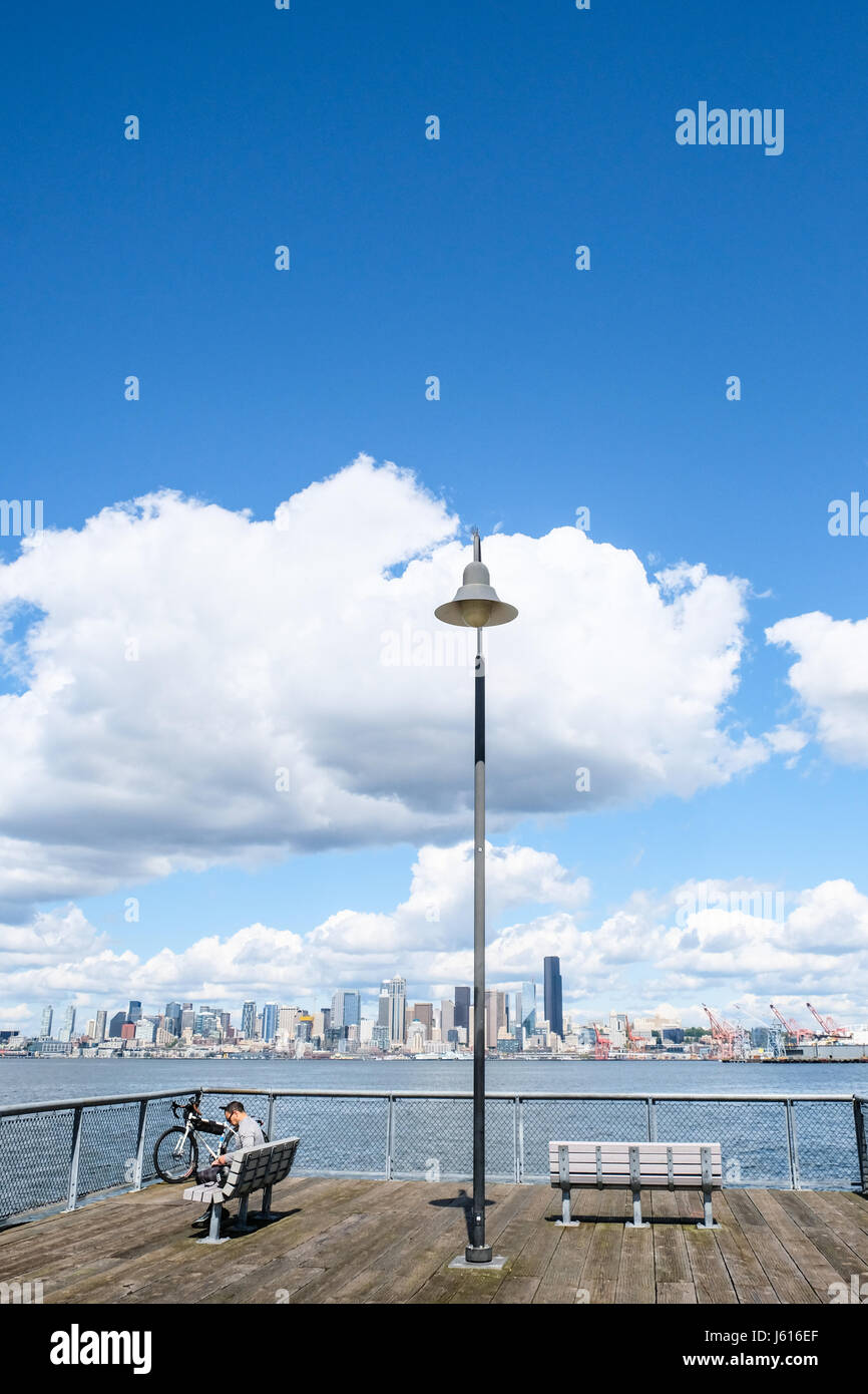 A biker relaxing at a waterfront park, with downtown Seattle skyline ...