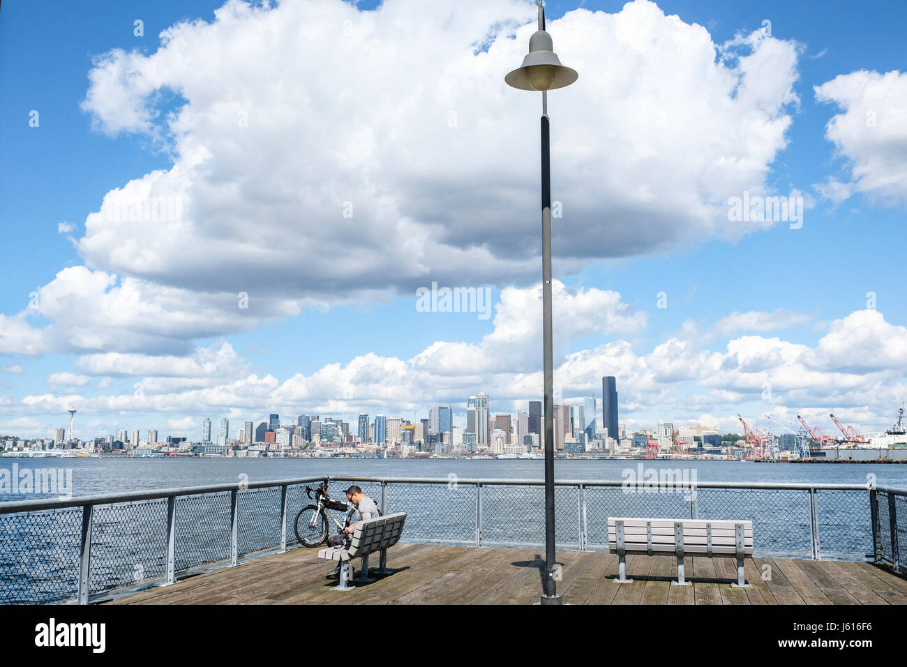 A biker relaxing at a waterfront park, with downtown Seattle skyline ...