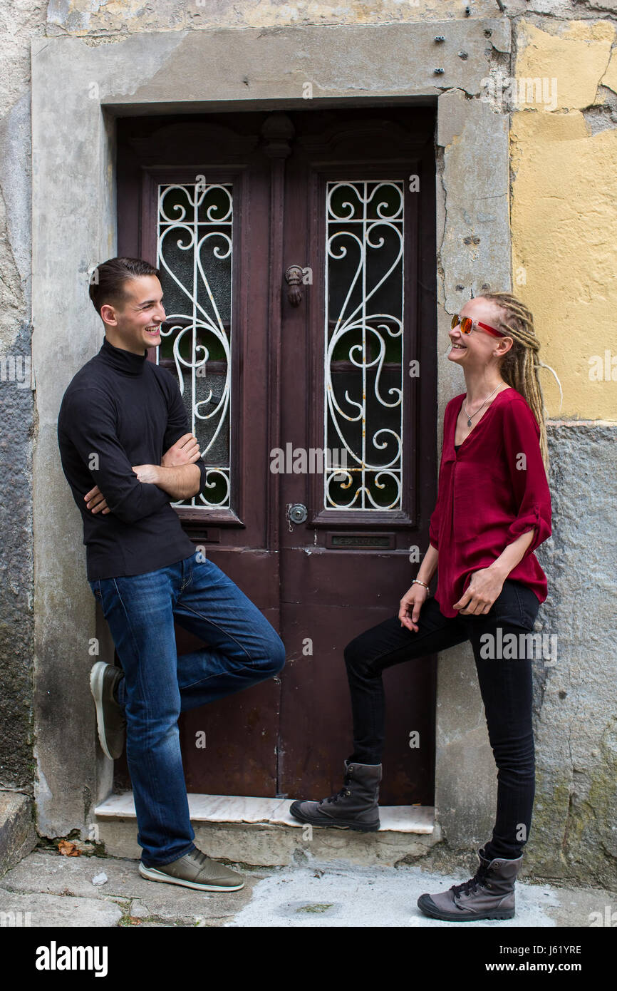 Young man and girl talking near the old wooden doors on the street ...