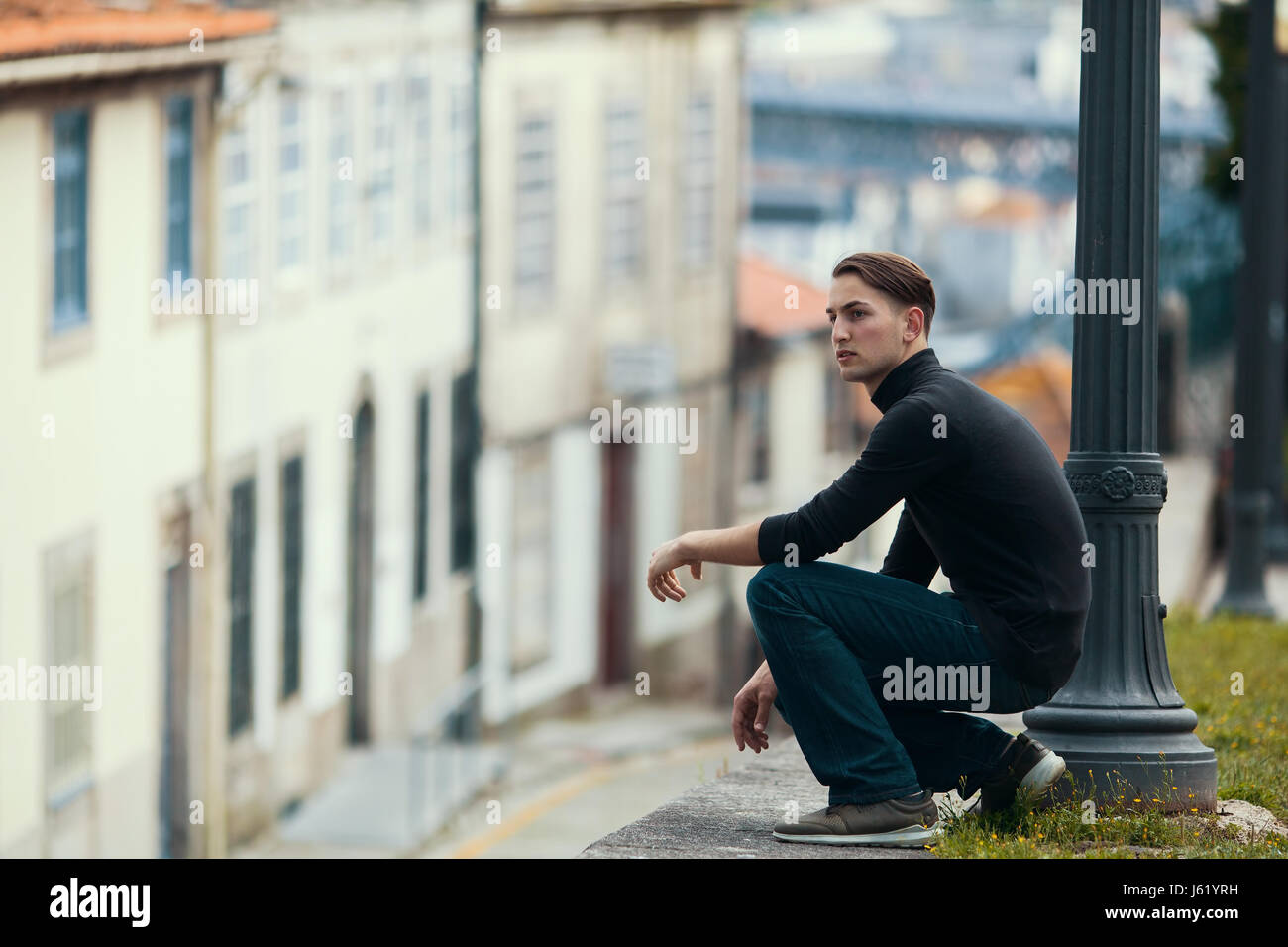 Young man sitting on the street in old european downtown Stock Photo ...