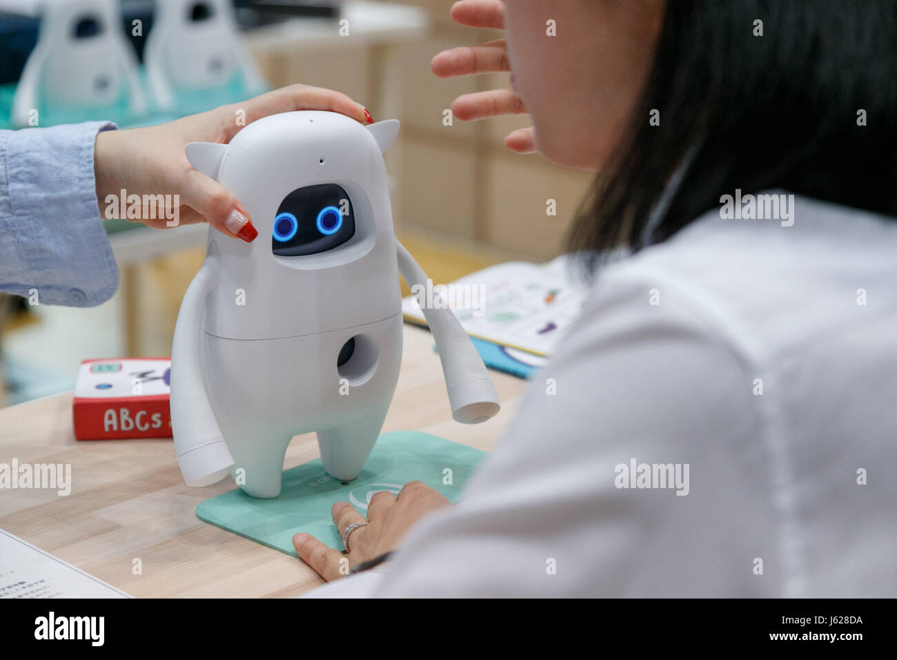 An exhibitor gives a demonstration to a visitor of an AI (Artificial ...