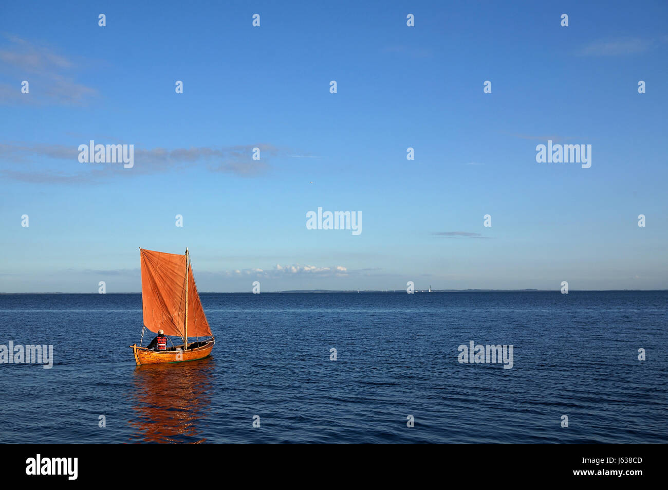 Small wooden boat with orange sail and anonymous person who controls ...