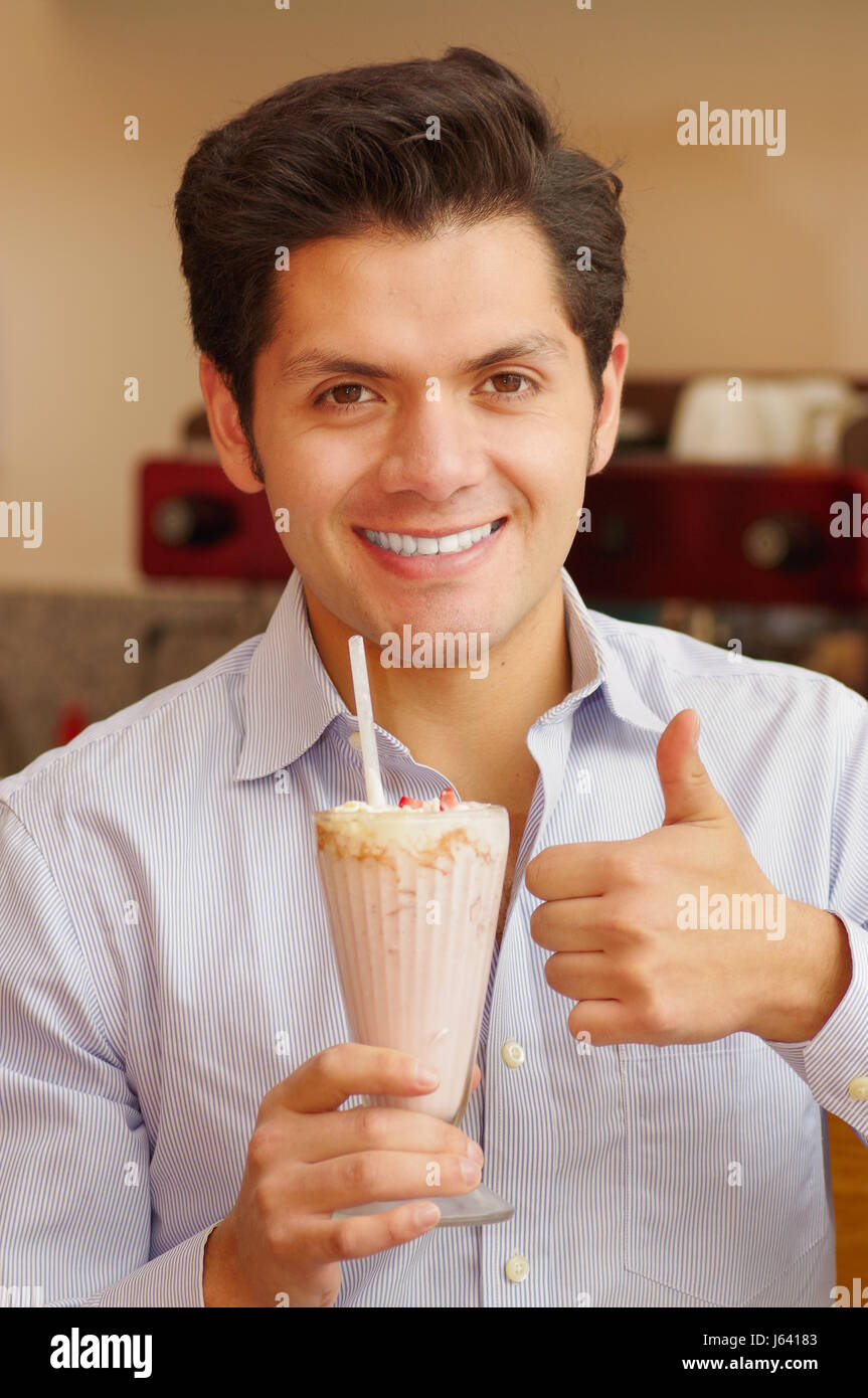 Handsome happy man having a milkshake with a plastic straw with thumb ...