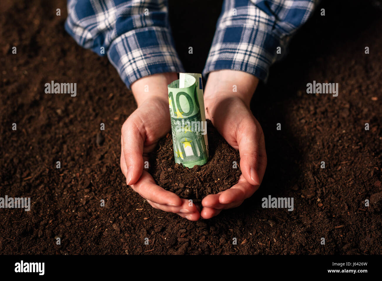 Hands with fertile soil and euro money banknotes, female farmer handful ...