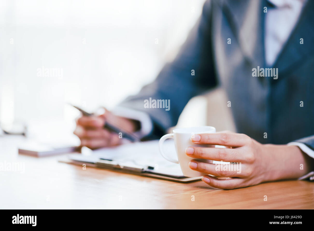 A businesswoman drink coffee while working in office Stock Photo - Alamy