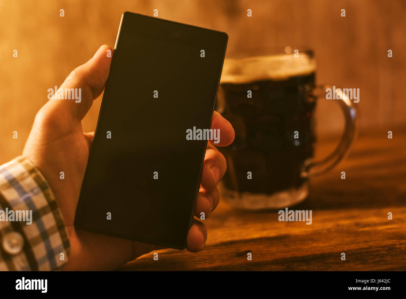 Man with mobile phone and dark beer mug sitting in the bar, drinking ...
