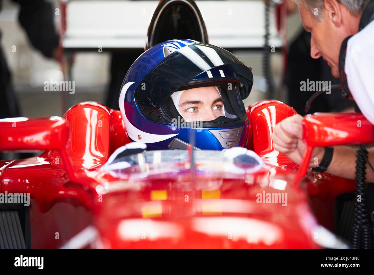 Manager talking to formula one race car driver Stock Photo - Alamy