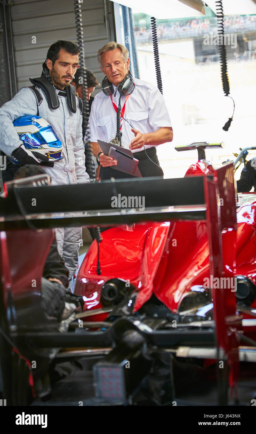 Manager and formula one race car driver talking in repair garage Stock ...