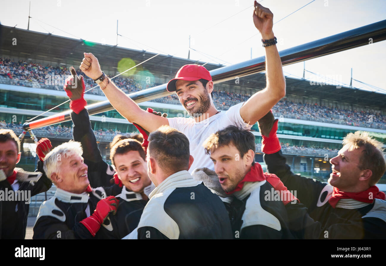 Formula one racing team carrying driver on shoulders, celebrating ...