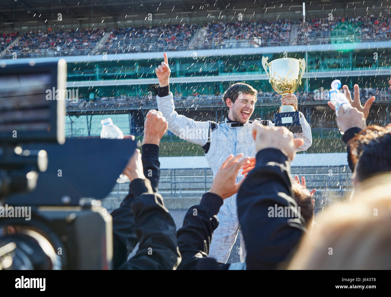 Formula one racing team spraying champagne on driver with trophy ...