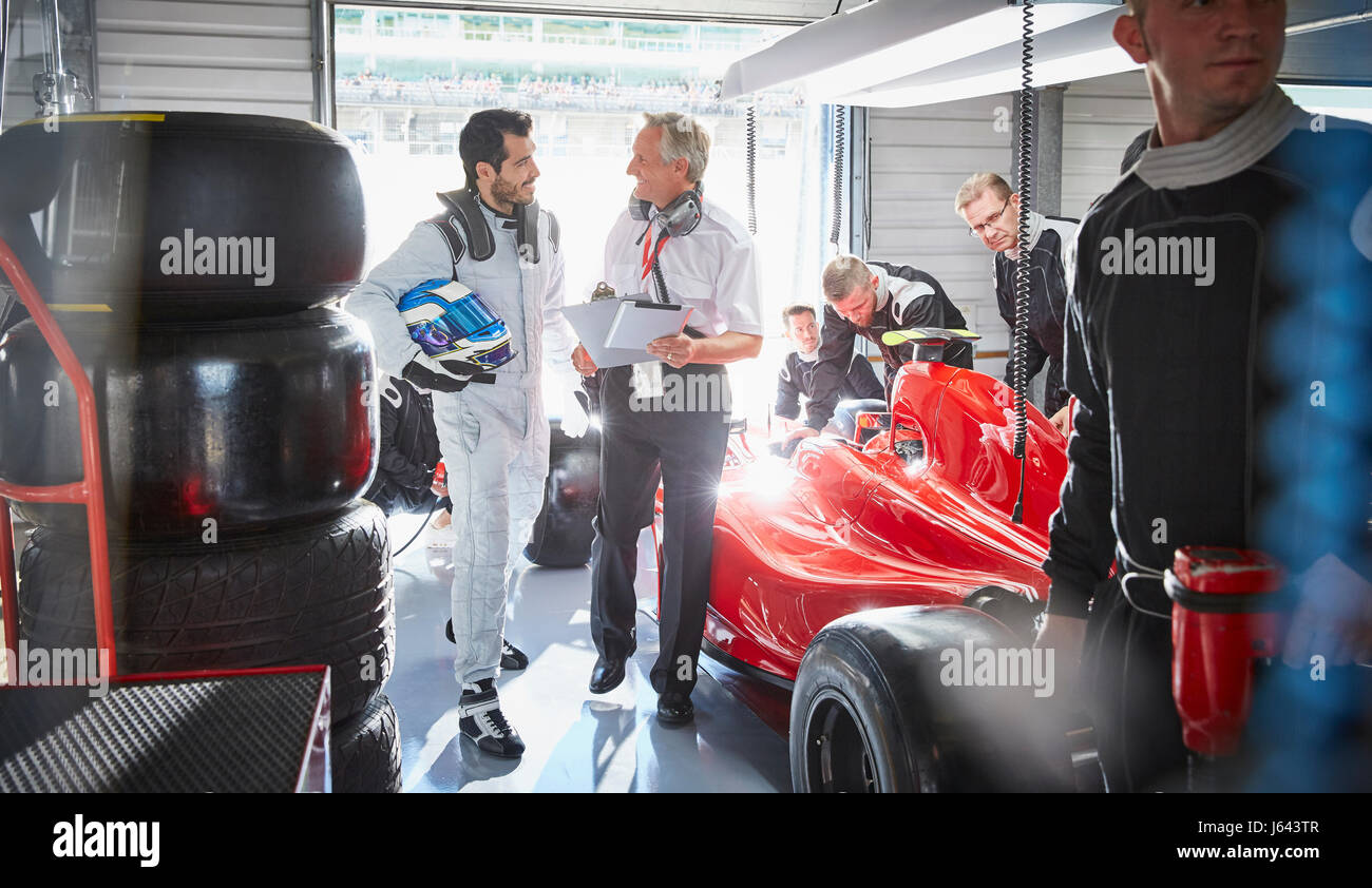 Manager and formula one race car driver talking in repair garage Stock ...