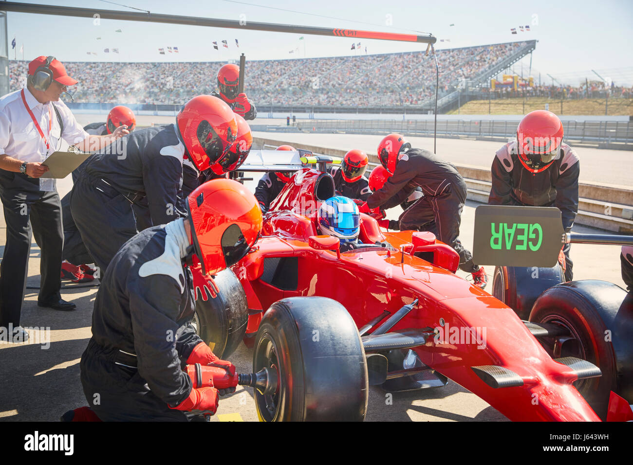 Pit crew replacing tires on formula one race car in pit lane practice ...