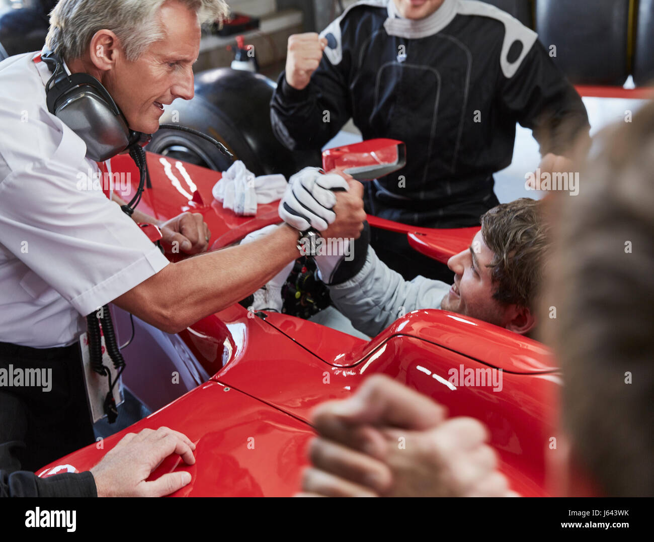 Manager and formula one race car driver handshaking, celebrating ...