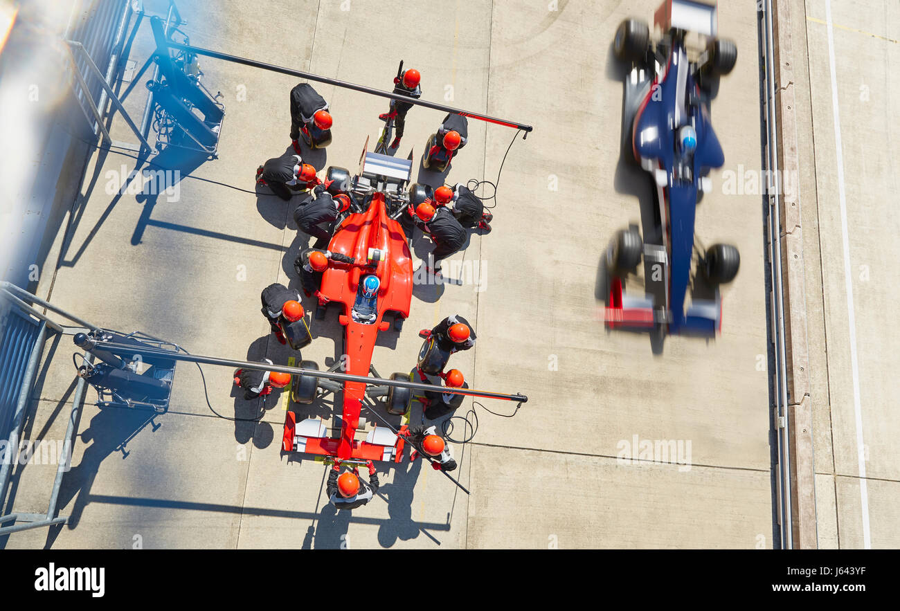 Overhead pit crew replacing tires on formula one race car in pit lane ...