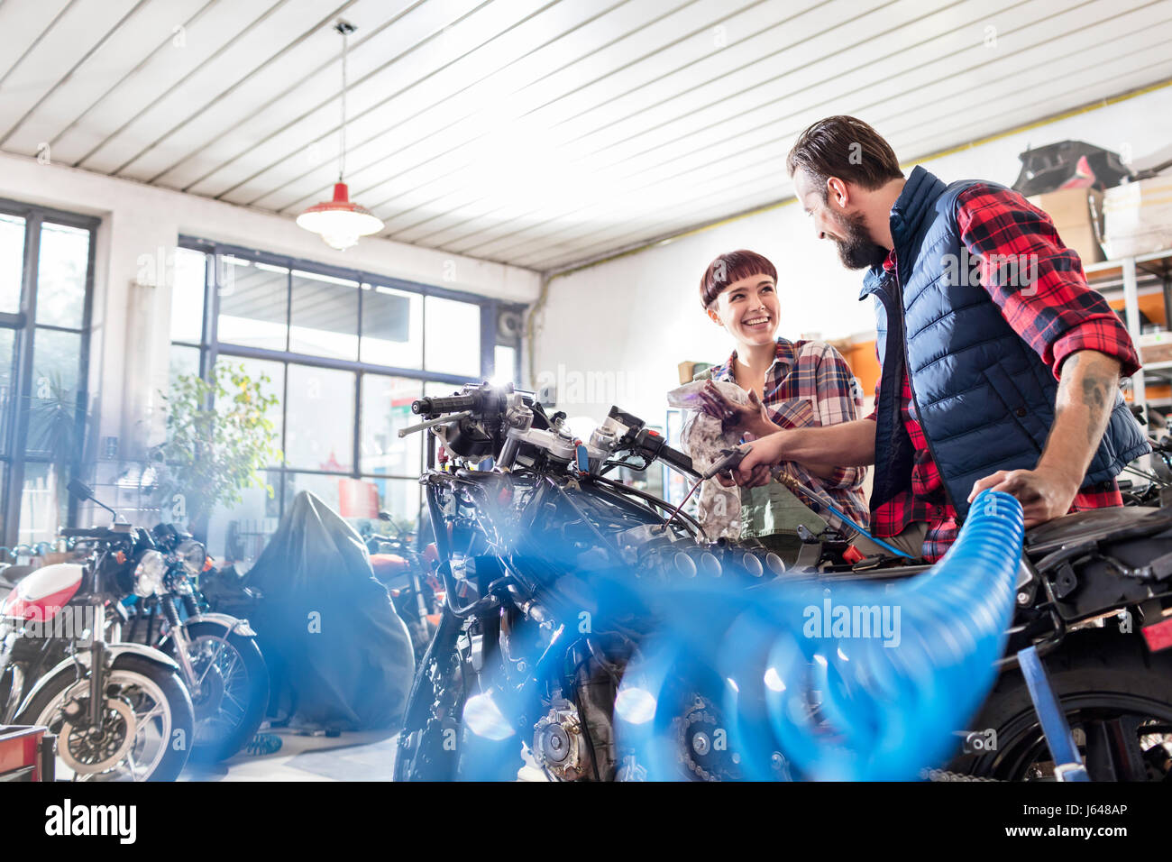 Male and female motorcycle mechanics repairing motorcycle in workshop ...