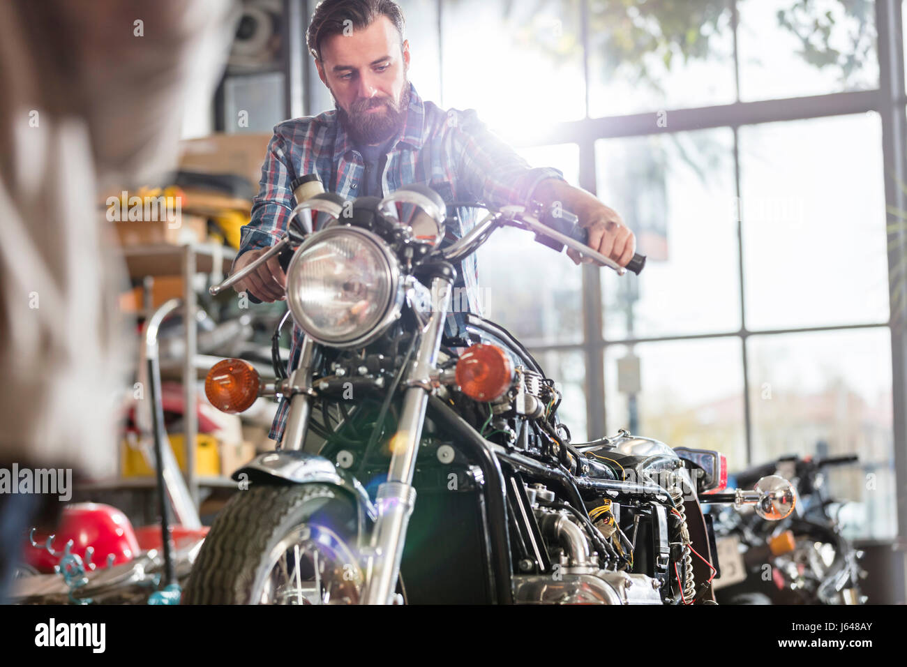 Male motorcycle mechanic working on motorcycle in workshop Stock Photo ...