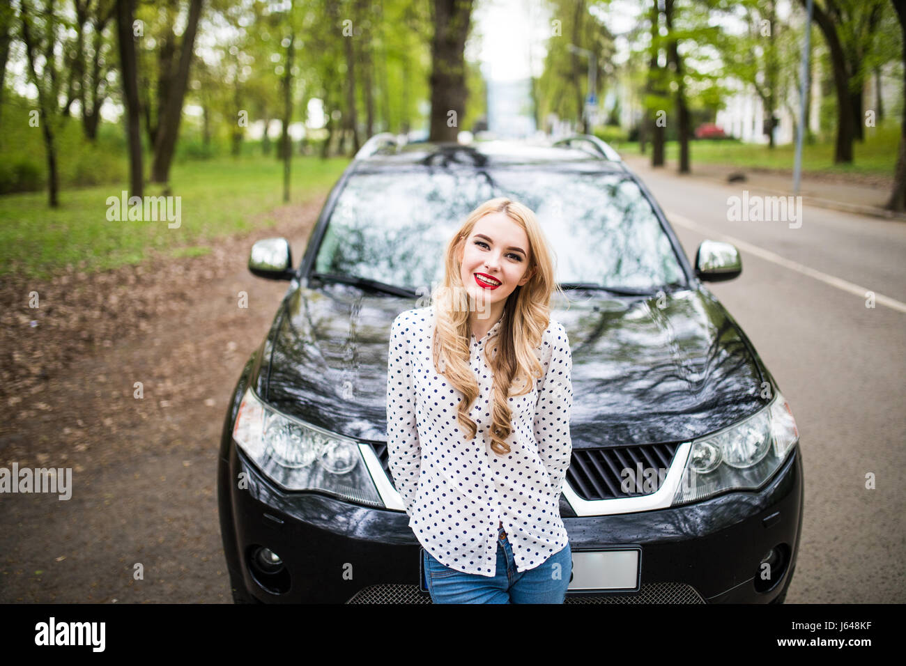 Young woman in front of her car on street Stock Photo - Alamy