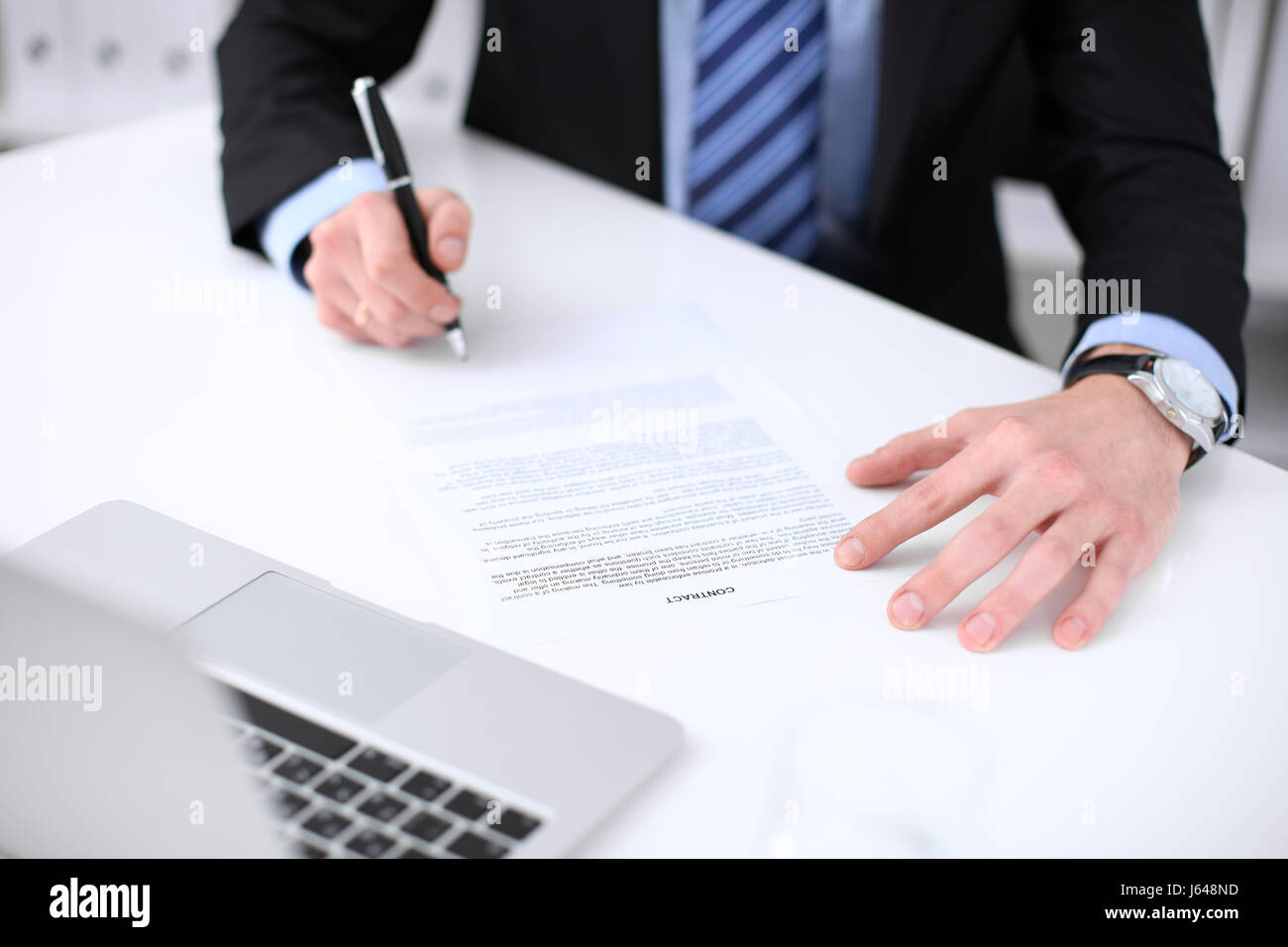 Young business man signs contract while sitting at the desk in office ...